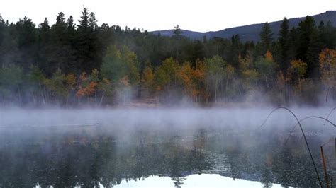 Early Morning Mist Over Lake Against A Background Of Fall Foliage