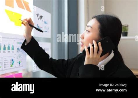 Asian Businesswoman In Office Analyzing Data Charts While Multitasking