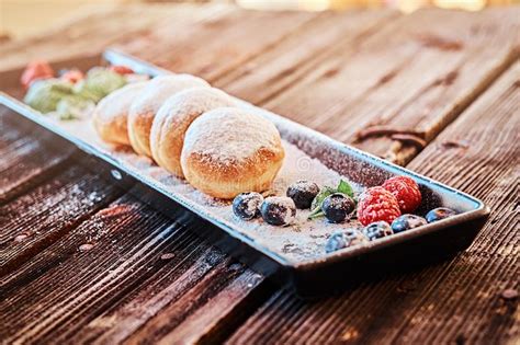 Donuts Sprinkled With Powdered Sugar On A Black Long Plate With