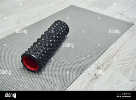 Modern Black Roller Massager Lying On Fitness Mat On Floor At Home