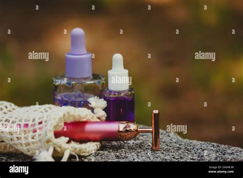 Golden T Shape Face Massager With Vibration Serum Bottles On A Stone