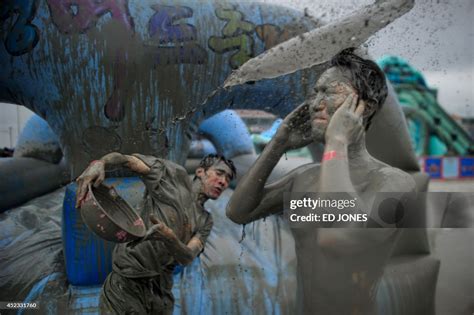 A Reveller Throws A Bucket Of Mud During The 17th Boryeong Mud News