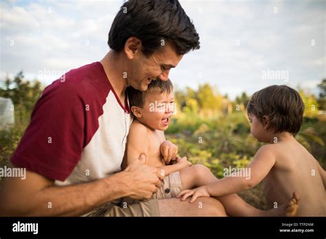 Father Playing With Shirtless Son At Community Garden Stock Photo Alamy