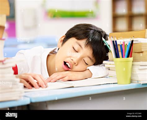 Tired And Exhausted Asian Primary School Student Falling Asleep While