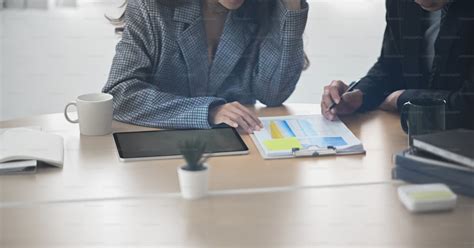 디지털 태블릿을 사용하는 두 명의 비즈니스 동료가 사무실에서 종이에 비즈니스 데이터를 분석하는 장면을 자릅니다 사진 Unsplash의 태국 이미지