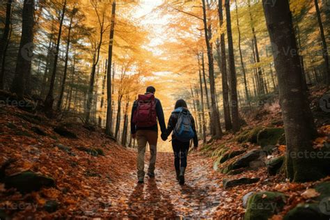 Couple Hiking On A Forest Trail Covered In Colorful Leaves