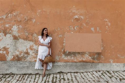 Caucasian Woman Wearing White Drees Standing In Front Of Orange