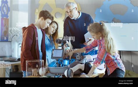 Teacher And His Pupils Work On A Programable Robot With Led