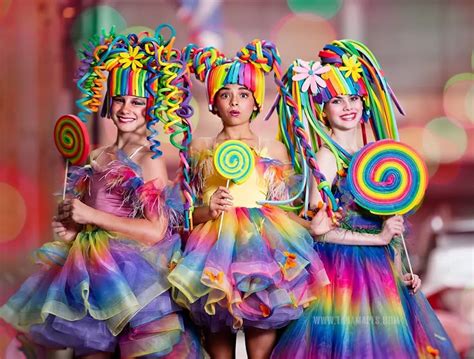 Three Girls Dressed In Colorful Costumes Holding Lollipops