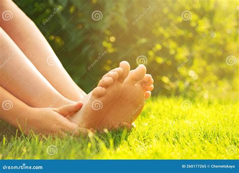 Teenage Girl Sitting Barefoot On Green Grass Outdoors Closeup Stock