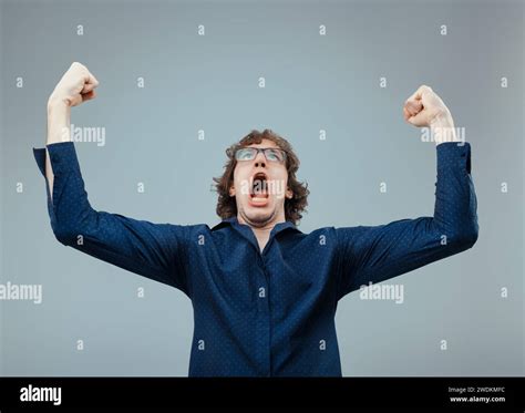 Exuberant Man Celebrates With Arms Raised Eyes Wide And Mouth Open In