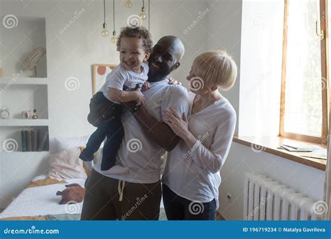 Familia Feliz Descansando En Casa Una Familia Multicultural Foto De Archivo Imagen De Hombres