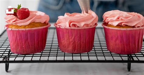 한 여성이 핑크색 아이싱으로 컵케이크를 장식하고 있습니다 사진 Unsplash의 무료 음식 이미지