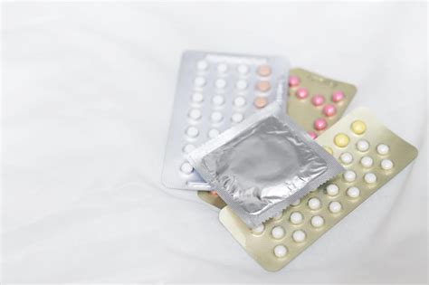 Premium Photo Pill Contraceptive And Condom On The Bed