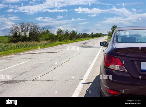 Rear View At The Passenger Car Stopped In Curb Of Asphalt Road