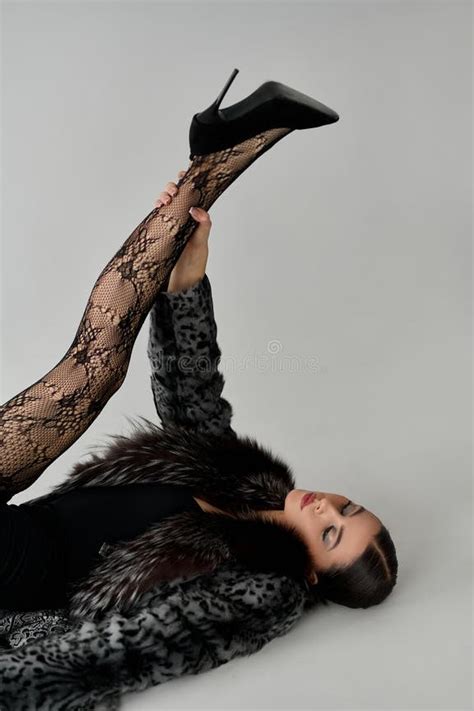 Woman In Leopard Fur Coat And Black Bodysuit Posing In Studio On White