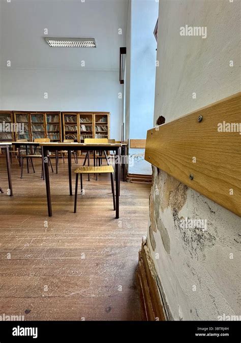Old Classroom With Wooden Desks And Visible Wall Damage School
