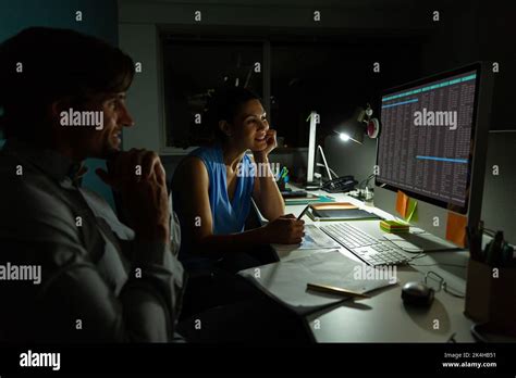 Two Diverse Male And Female Colleagues Sitting At Desk Using Computer With Coding On Screen