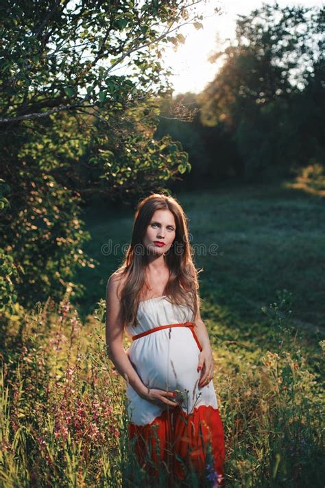 Young Pregnant Woman In The Park Outdoors Calm Pregnant Woman In Third