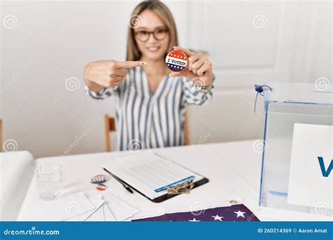 Young Chinese Woman Sitting On Election Table Holding Badge At