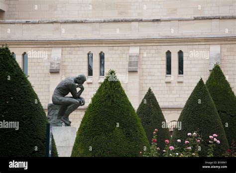 The Thinker Statue Surrounded By Roses And Shrubs In The Gardens Paris