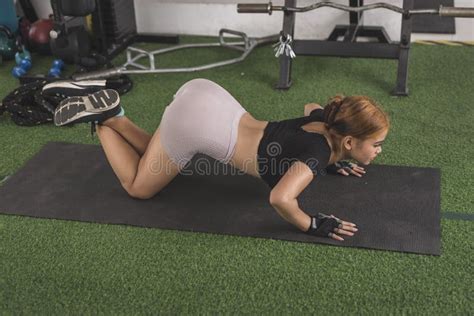 A Young Slim And Asian Woman Does Knee Push Ups On A Black Mat