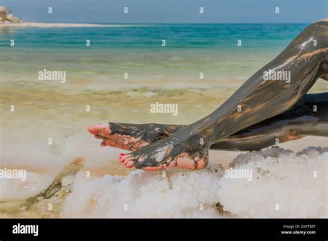 Woman Relaxing With Legs Covered In Mud From Dead Sea In Jordan