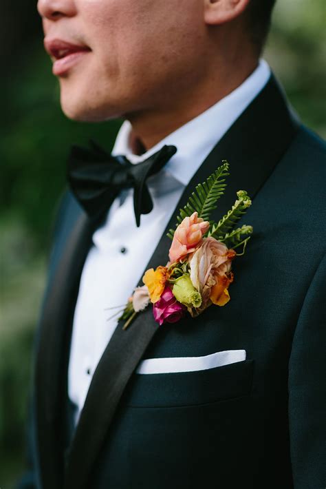Groom In Black Tuxedo With Colorful Tropical Boutonniere And Greenery