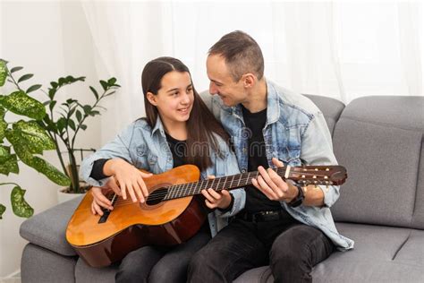Father Guy Teaching Girl Teenager Daughter Guitar Playing At Home