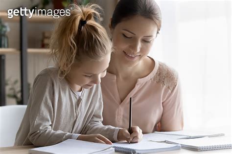 Helping Young Mom Engaged In Learning Activity With Preteen Daughter