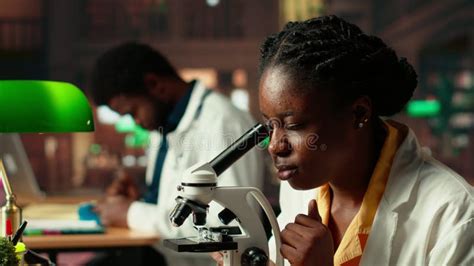 Female Science Student Examines Cells Under Microscope For Scientific
