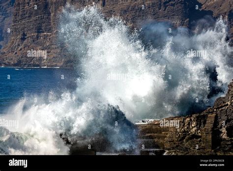 The Mighty Ocean Sends A Massive Wave Crashing Against The Rocky Shore