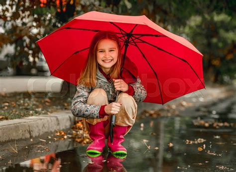 Preteen Girl Wearing Rubber Boots Sitting Under Umbrella At Colourbox