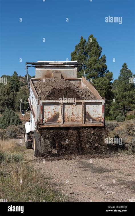 Old White Dump Truck Laying Gravel On A Road In A Remote Part Of