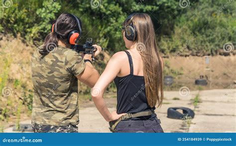 White Woman And Man Wearing Safety Gear At Outdoor Shooting Range Practicing Firing Submachine