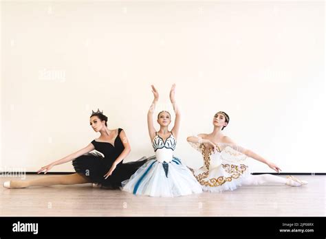 Three Young Ballerinas Perform Paired Exercises Against A White