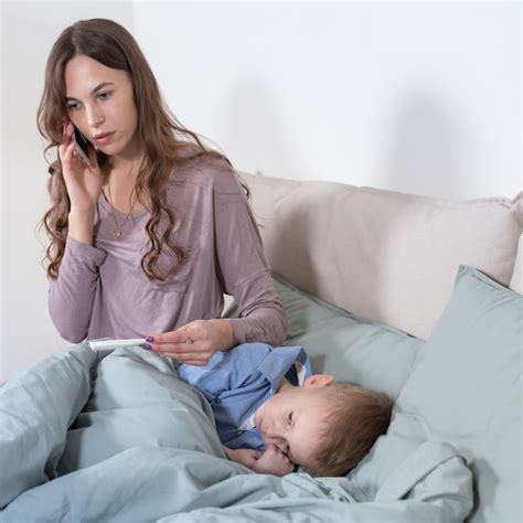 Madre Joven Preocupada Midiendo La Temperatura De Su Hijo Y Llamando A Un Médico Foto Premium