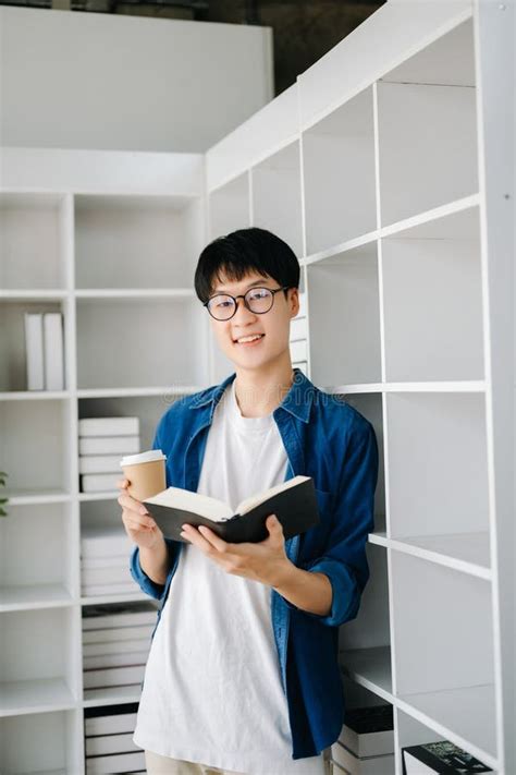Male Student Taking Notes From A Book At Library Young Asian Sitting