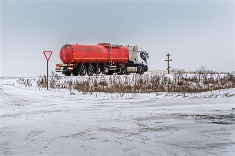 Oil Tanker Truck With A Red Tank Truck Driving Along A Winter Highway