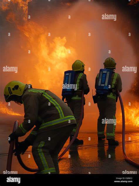Firefighters Fighting Fire Using Hose And Breathing Apparatus In