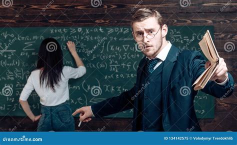 Genius Man In Glasses With Book Point At Woman Solving Equation On Chalkboard Genius Teacher
