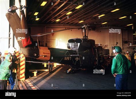 Squadron Personnel Examine A Uh 1n Iroquois Helicopter On The Hangar Deck Of The Amphibious