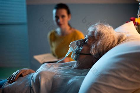 医院的一位女士在晚上帮助一位戴氧气面罩的图片 包图网企业站