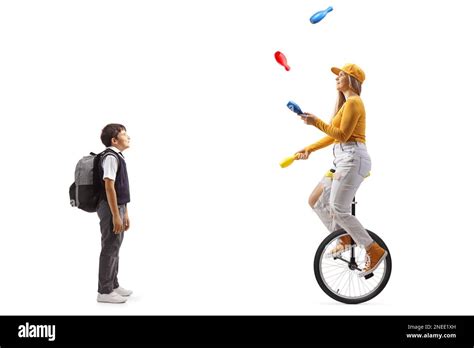 Boy Standing And Watching A Female Riding A Mono Cycle And Juggling