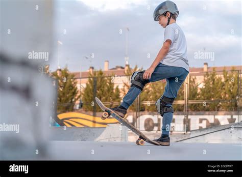 Low Angle Side View Of Brave Teen Skater Standing On Skateboard And