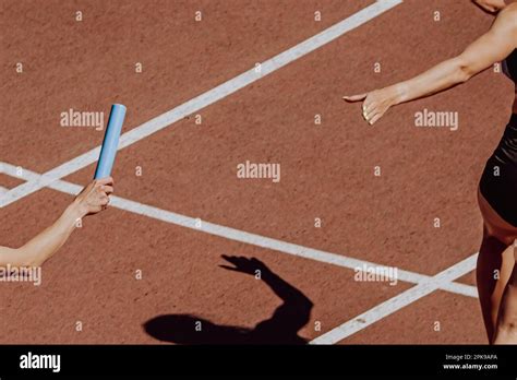 Hand Women Runner Passing Baton Running Relay Race In Summer Athletics