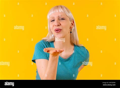 Smiling Blowing A Kiss To Camera Blonde Caucasian Girl In Studio On Yellow Background Stock