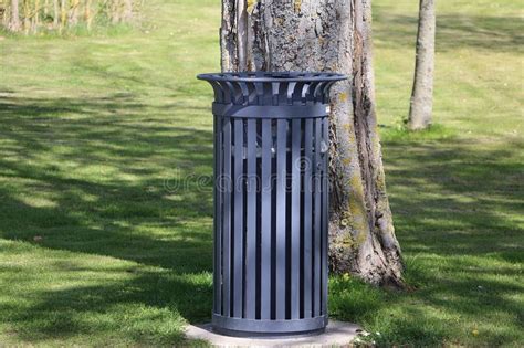 A Close Up Of A Stylish Metal Trash Can Standing Next To A Tree In A Park Stock Image Image Of