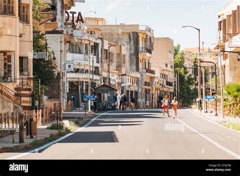 Tourists Walk Along A New Road Between Abandoned Buildings In The Ghost Town Of Varosha