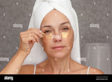 Woman Of 40s After Shower With Towel On Head With Gold Patches Under